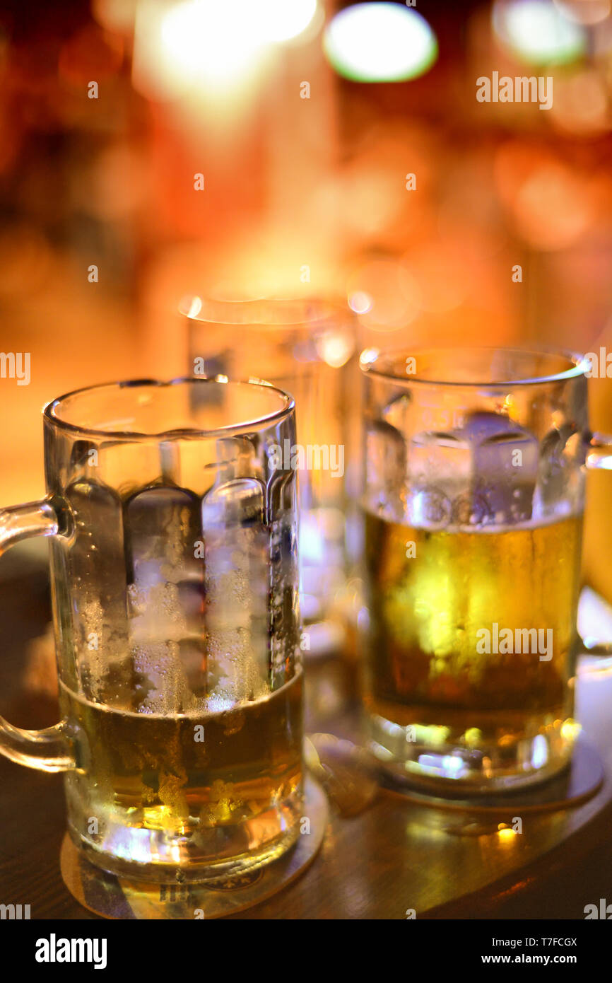 Ice cold beer in the pints yellow background Stock Photo - Alamy