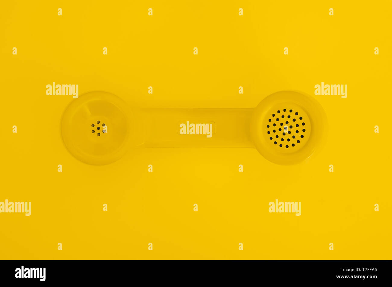 A retro yellow telephone handset centered on a yellow background Stock ...
