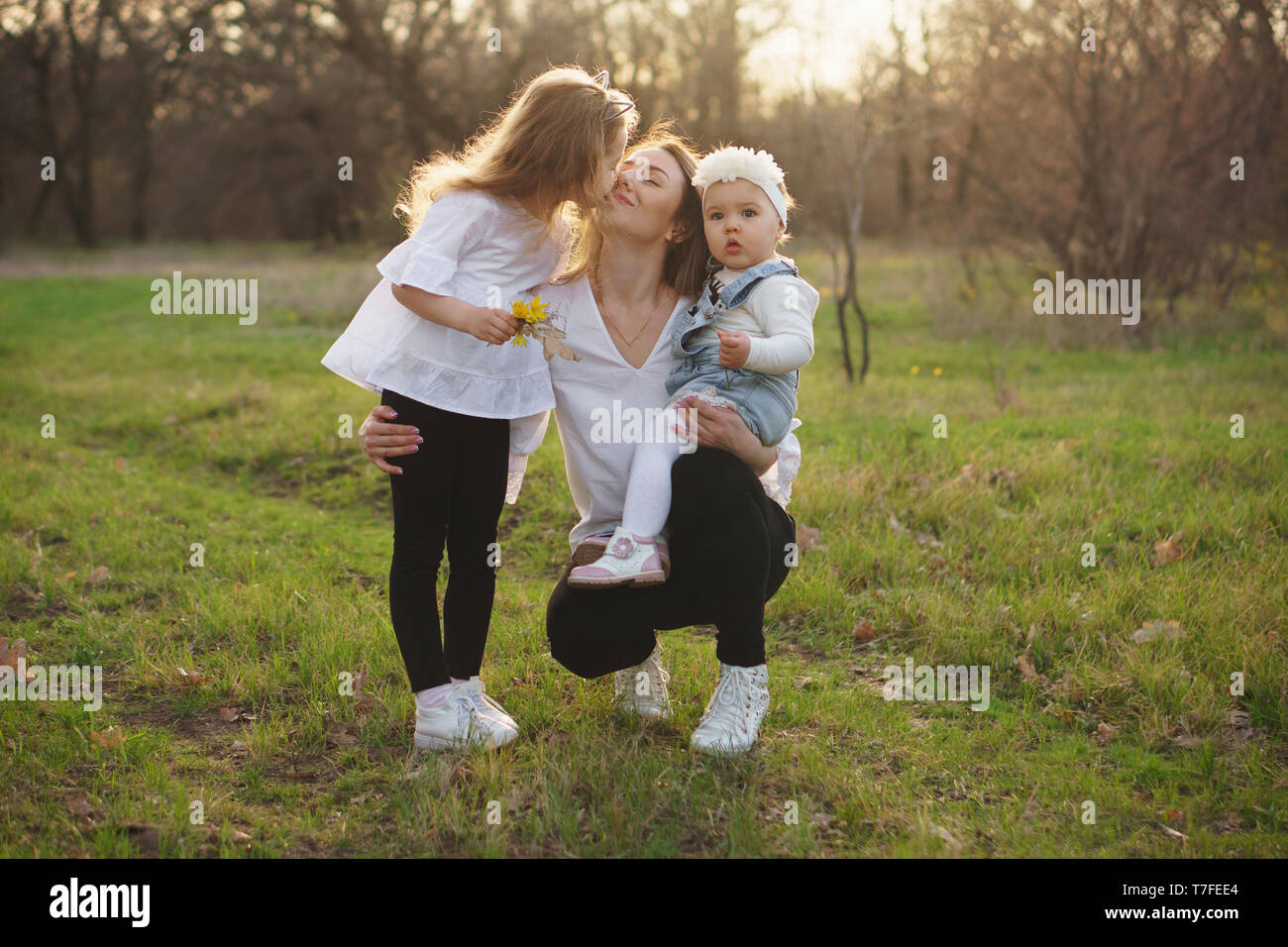 Family spring portrait. Oldest daughter kisses mom. Single mother holds ...