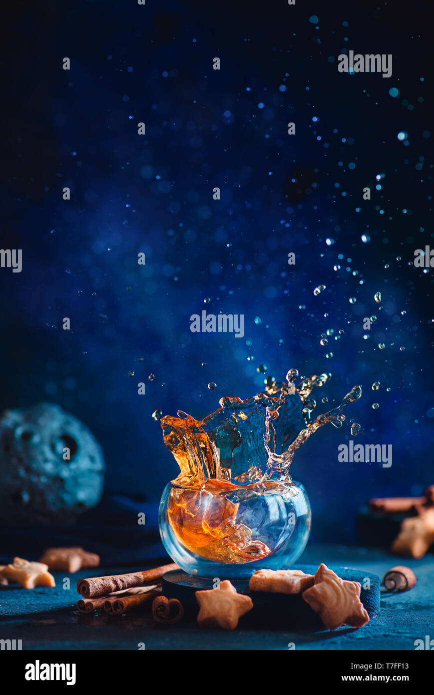 Tea splash in a double wall glass tea bowl with star-shaped cookies on ...