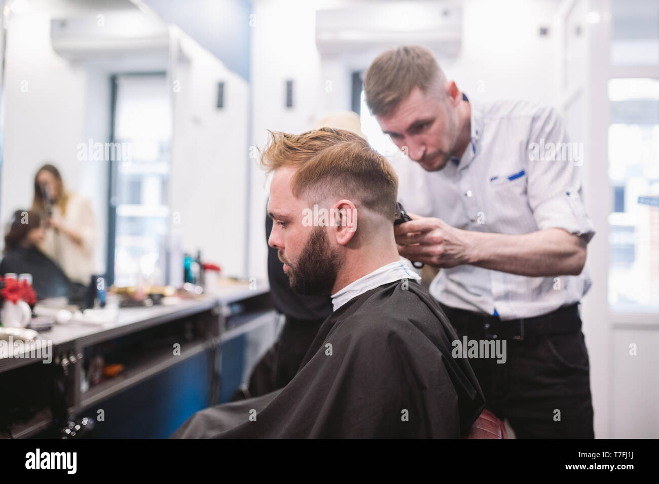 Close up shot of a man getting a trendy haircut at a hair salon. Male ...