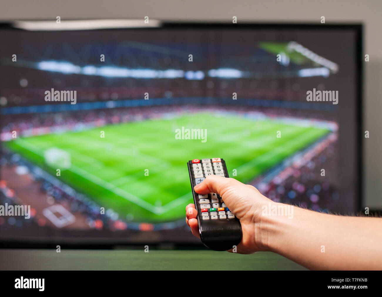 Man watching football match on television at home, the remote control ...