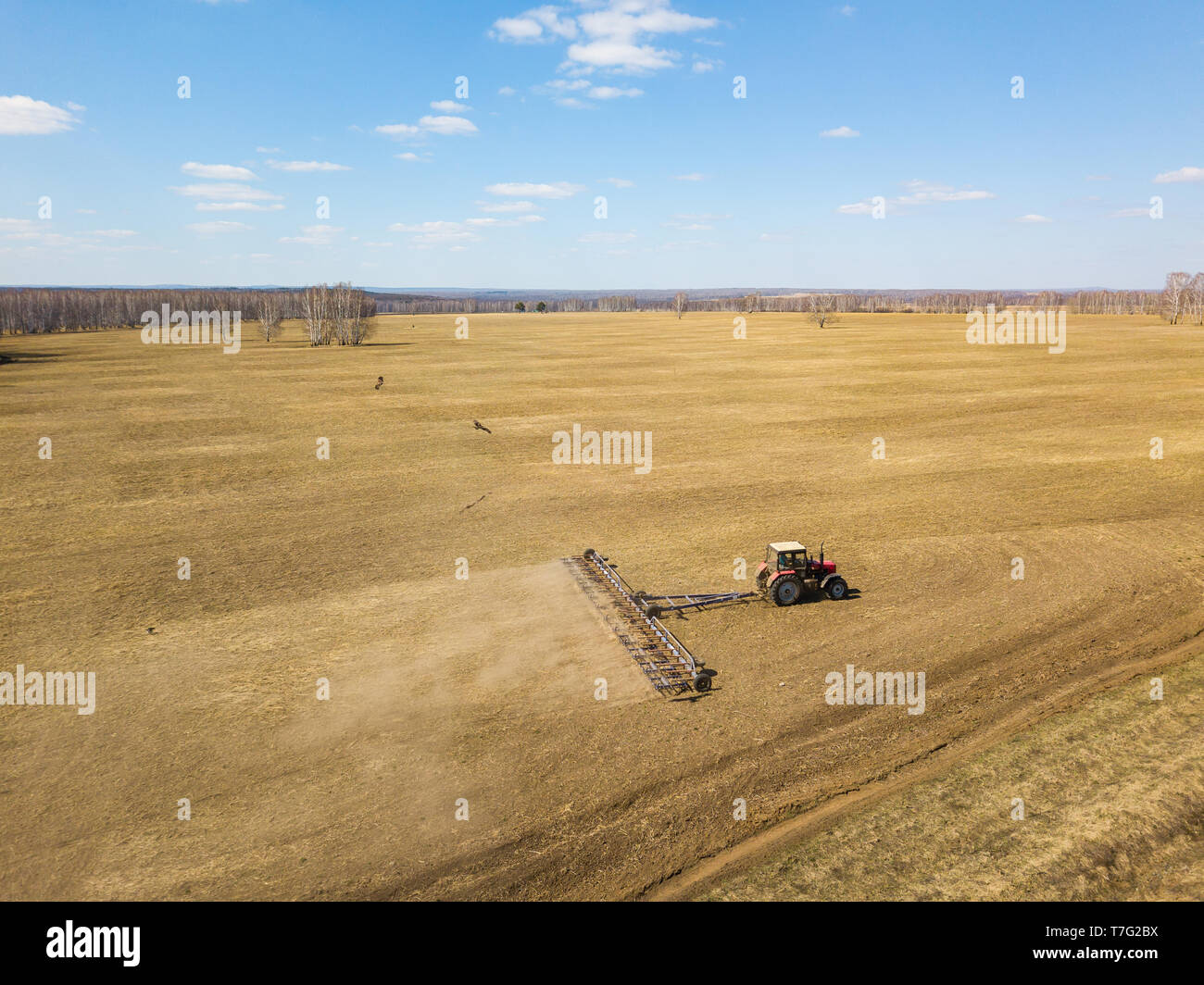 Aerial of Red tractor with a trailed plow for mowing and weeding fields ...