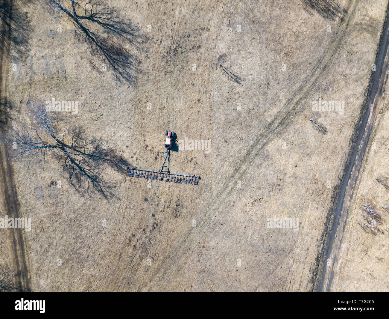 Aerial of Red tractor with a trailed plow for mowing and weeding fields ...