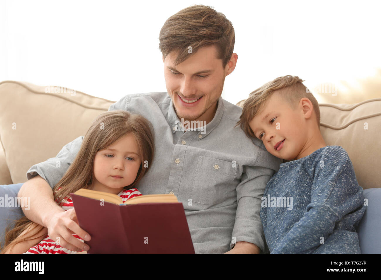 Father and his children reading book together at home Stock Photo - Alamy