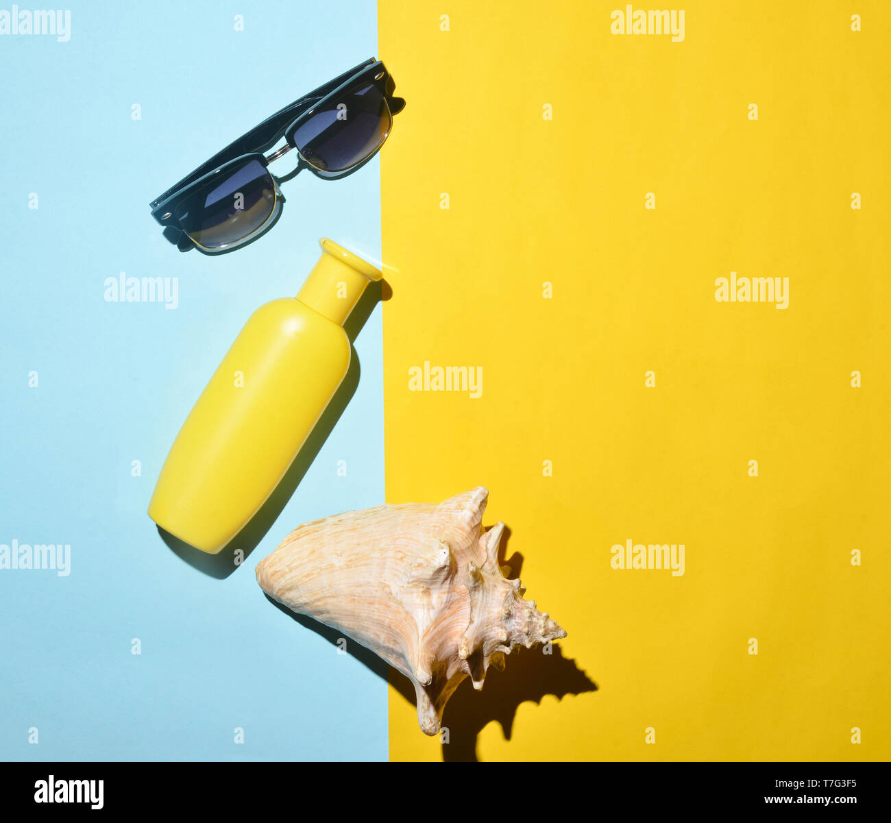 Sunglasses, sunblock, shell on a blue yellow background. Summer beach ...