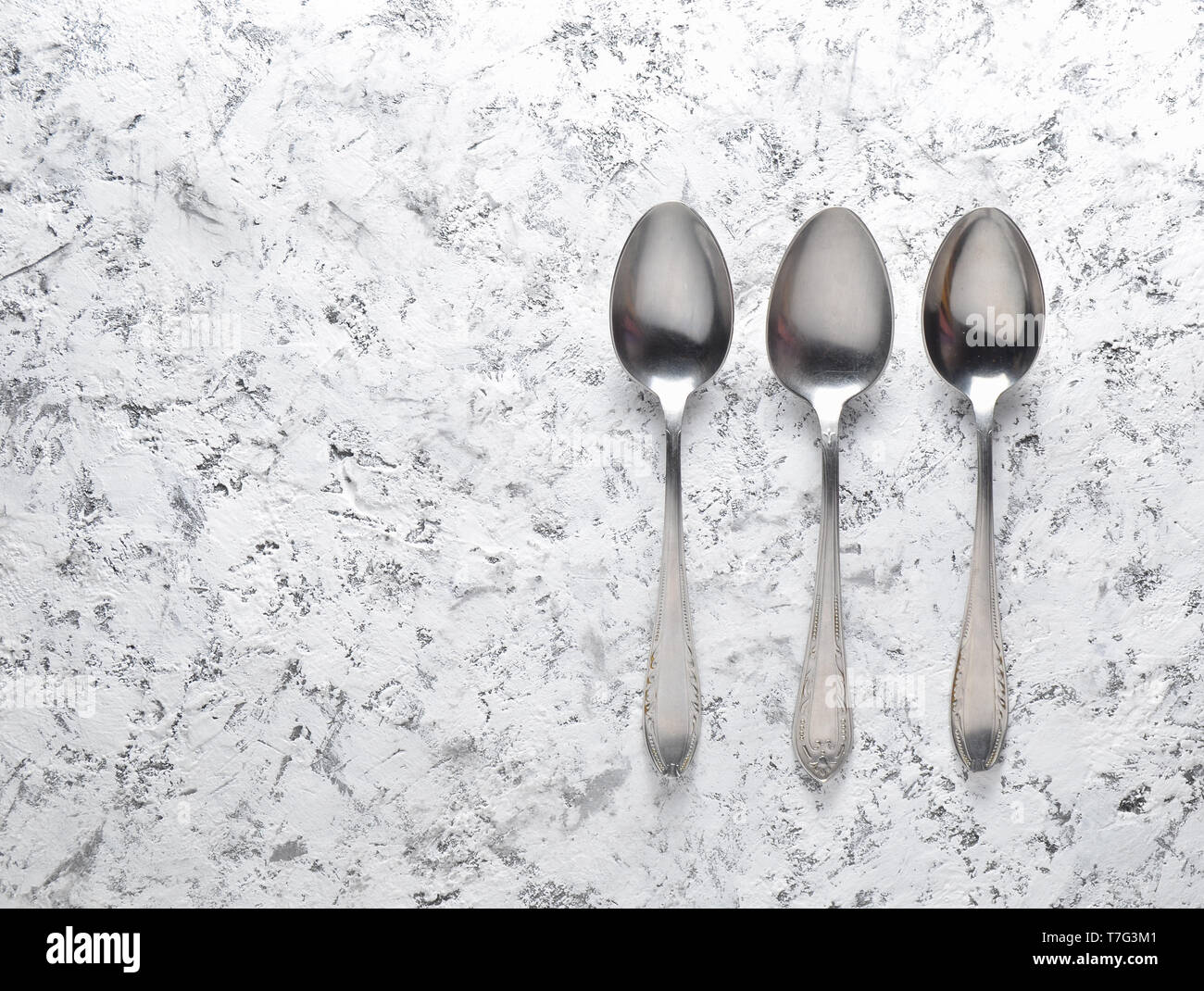 A set of metal spoons on a white concrete surface. Top view Stock Photo ...