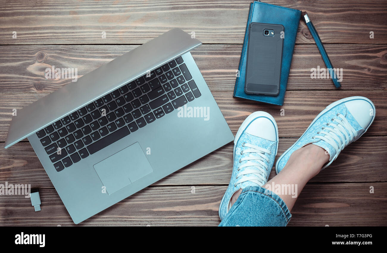 Female legs in jeans and sneakers, a laptop, a smartphone, a purse on a ...