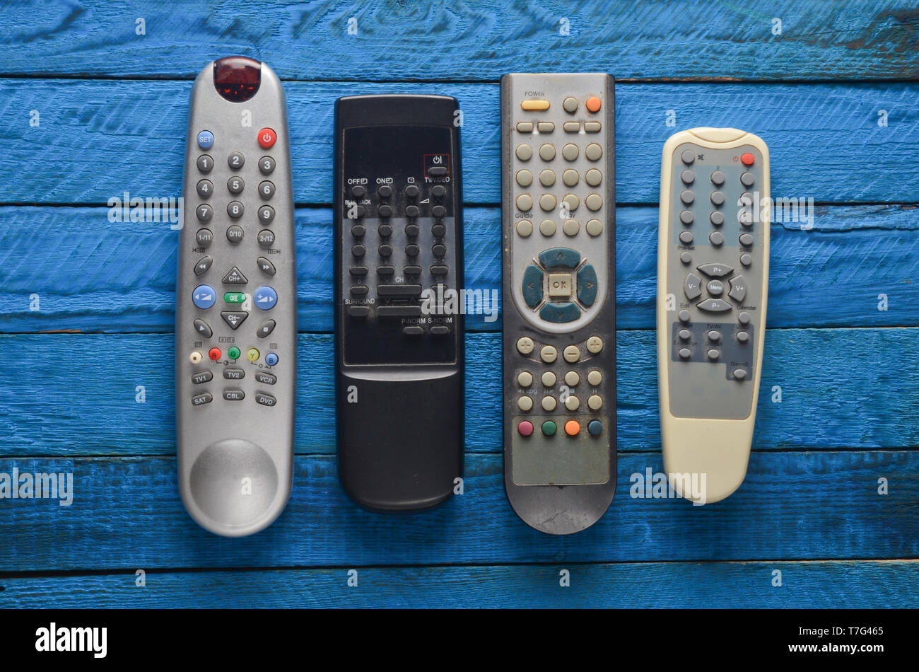 Many obsolete TV remotes on a blue rustic wooden table. Top view Stock ...