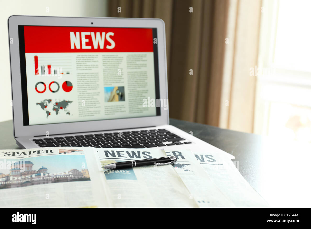 Laptop with open website and newspapers on table indoors Stock Photo ...