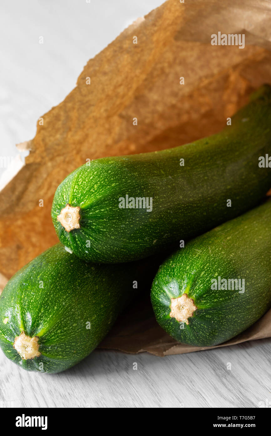 Organic courgette in a brown paper bag on grey wood. Recycle packaging ...