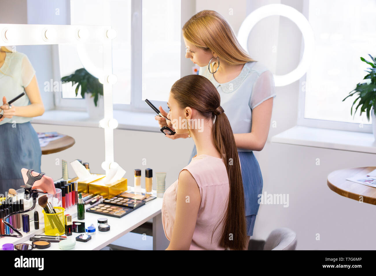 Beautiful young women looking into the mirror Stock Photo - Alamy