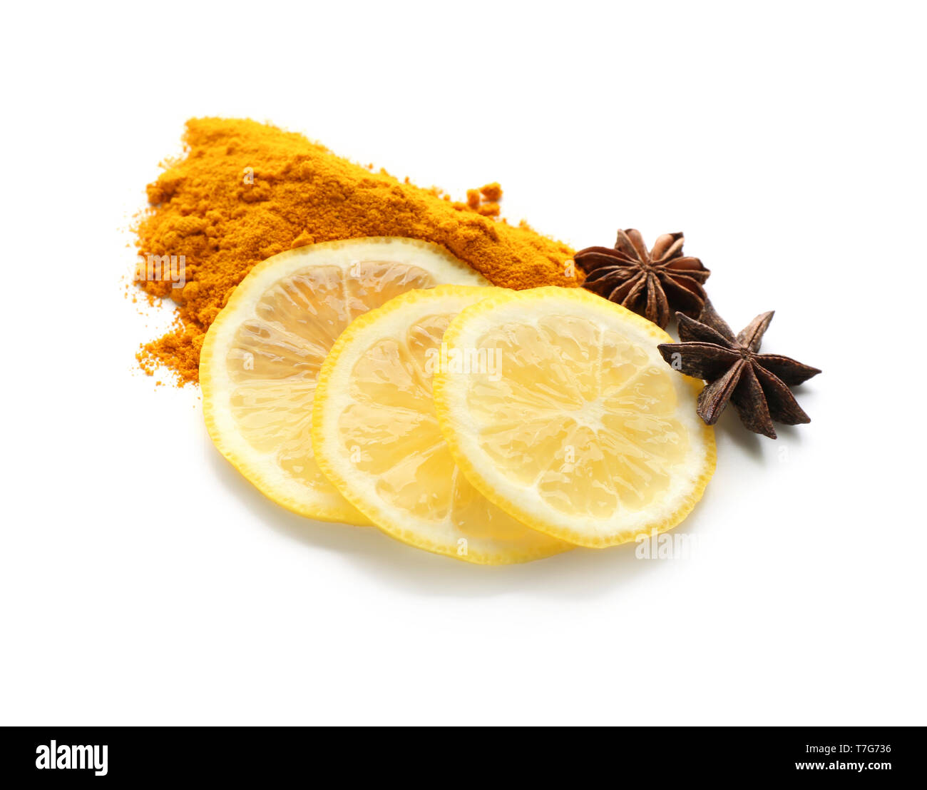 Turmeric powder with anise stars and sliced lemon on white background ...