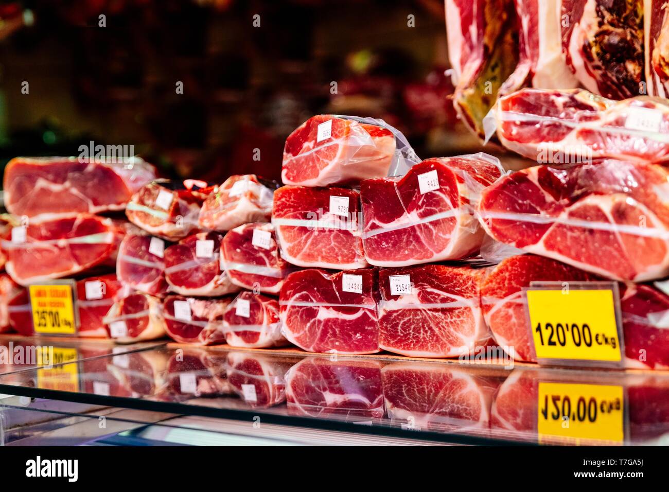 Traditional smoked Spanish ham on display in butcher stand on market ...