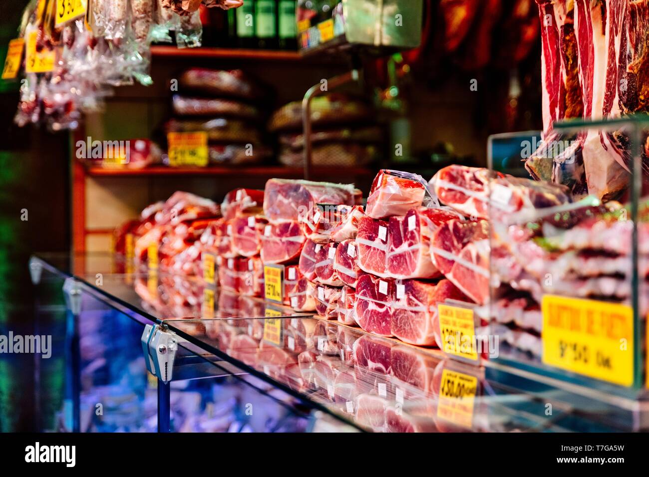 Traditional smoked Spanish ham on display in butcher stand on market ...
