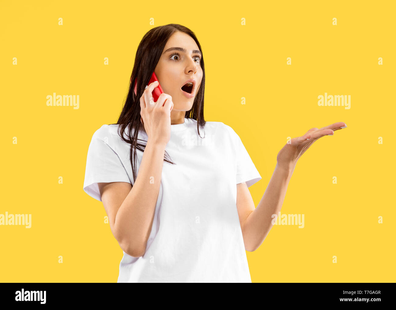 Astonished girl talking on the phone. Beautiful female half-length ...