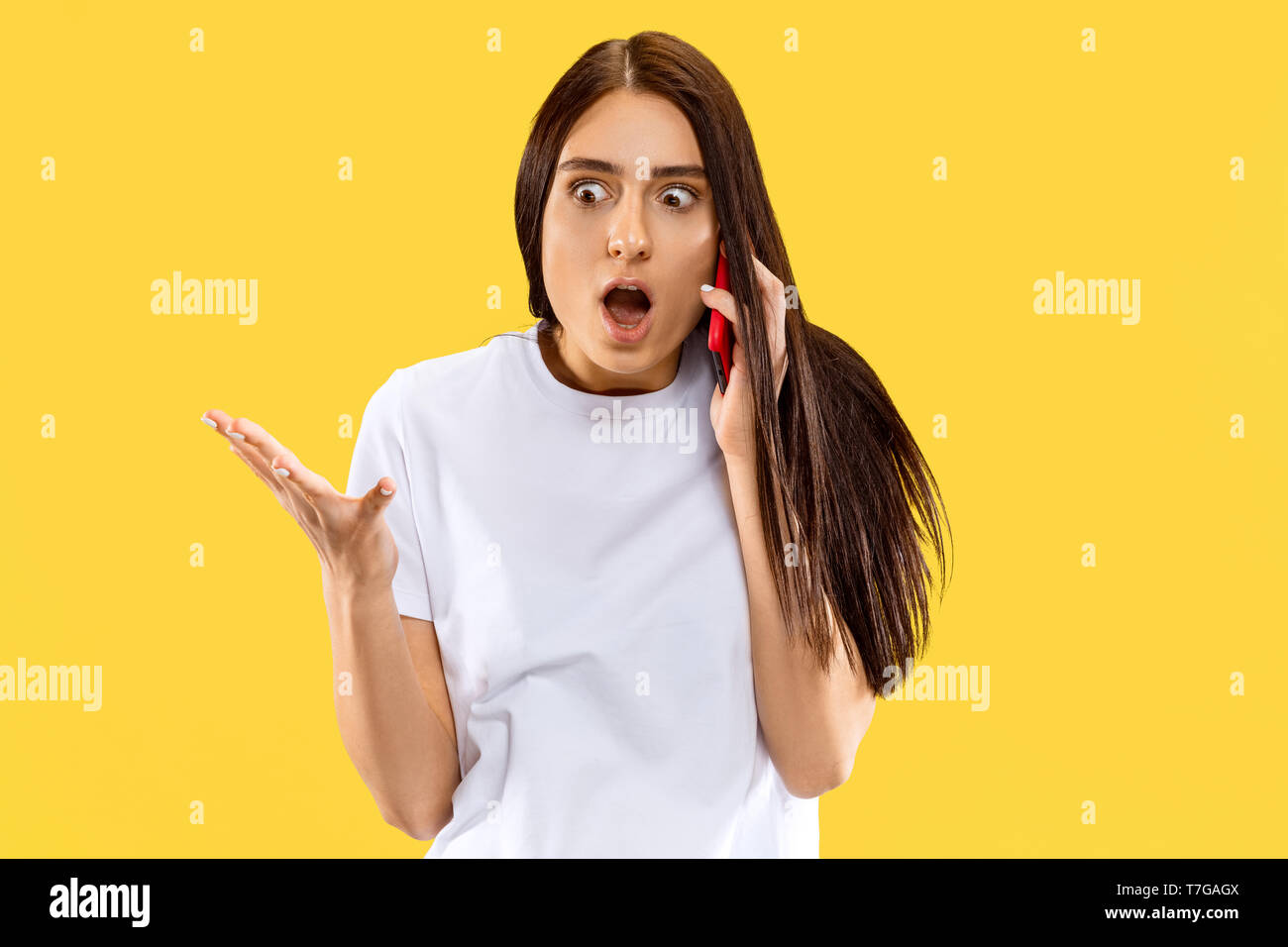 Astonished girl talking on the phone. Beautiful female half-length ...