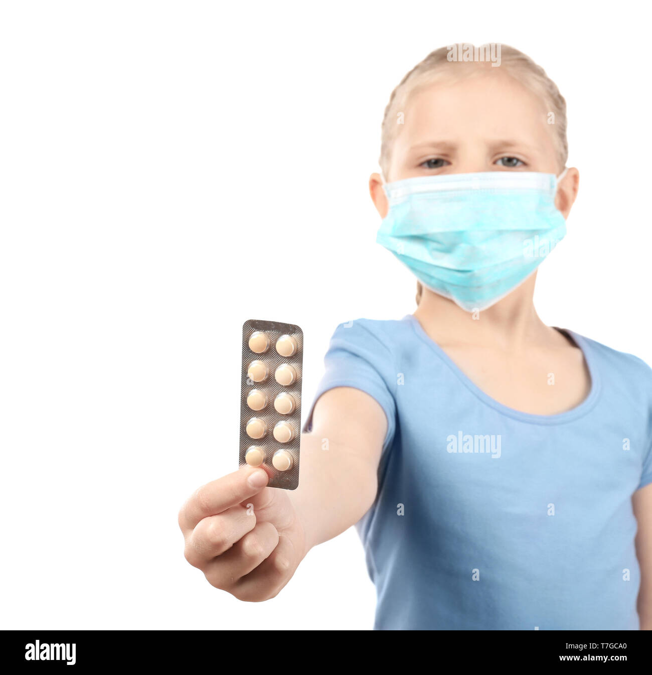 Little girl in protective mask holding pills on white background ...