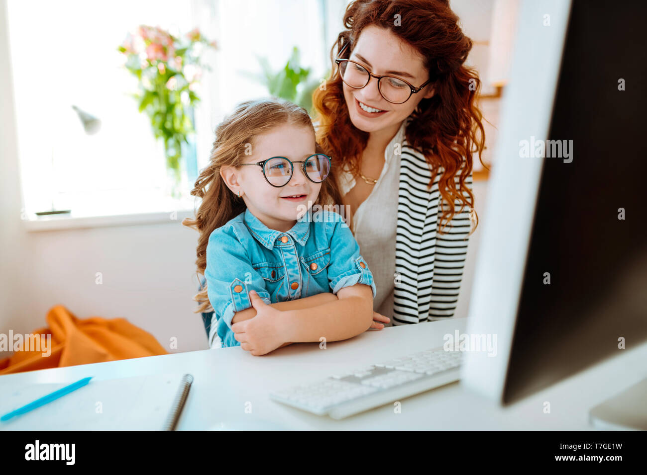 Daughter looking at screen of computer joining mother at work Stock ...