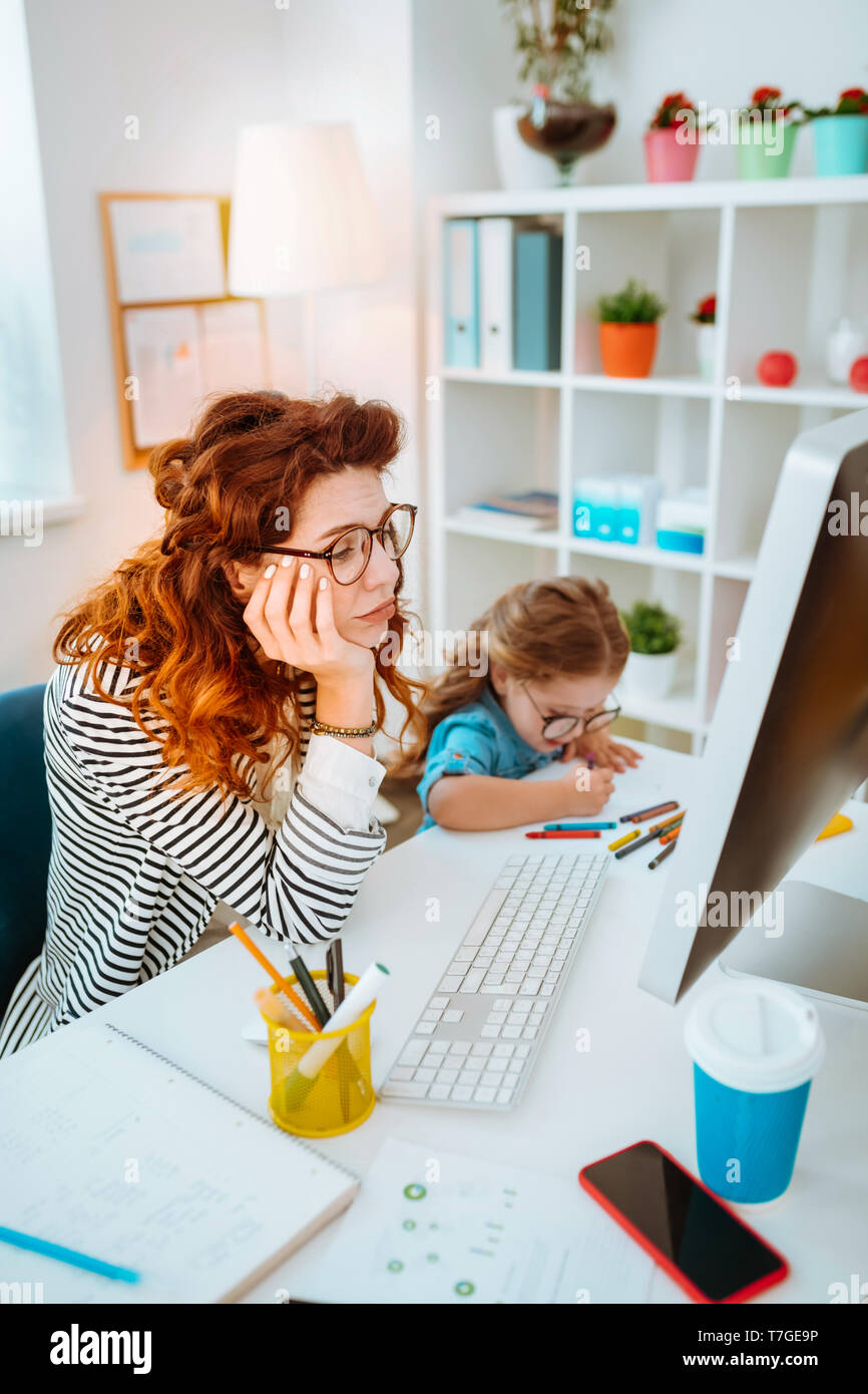 Mom working remotely having many tasks while sitting near daughter ...