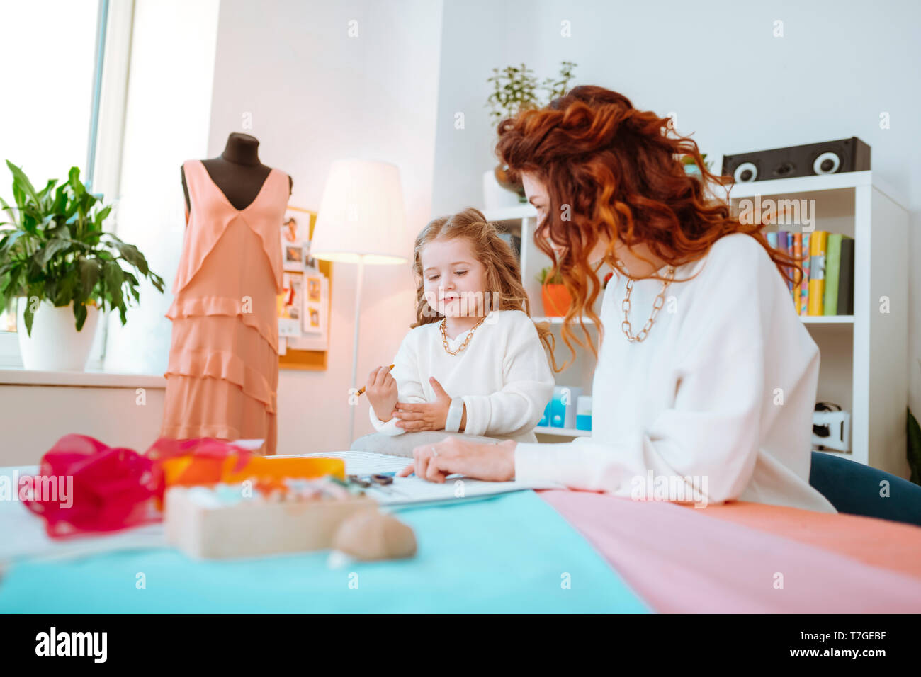 Red-haired designer designing sketches with her lovely girl Stock Photo ...