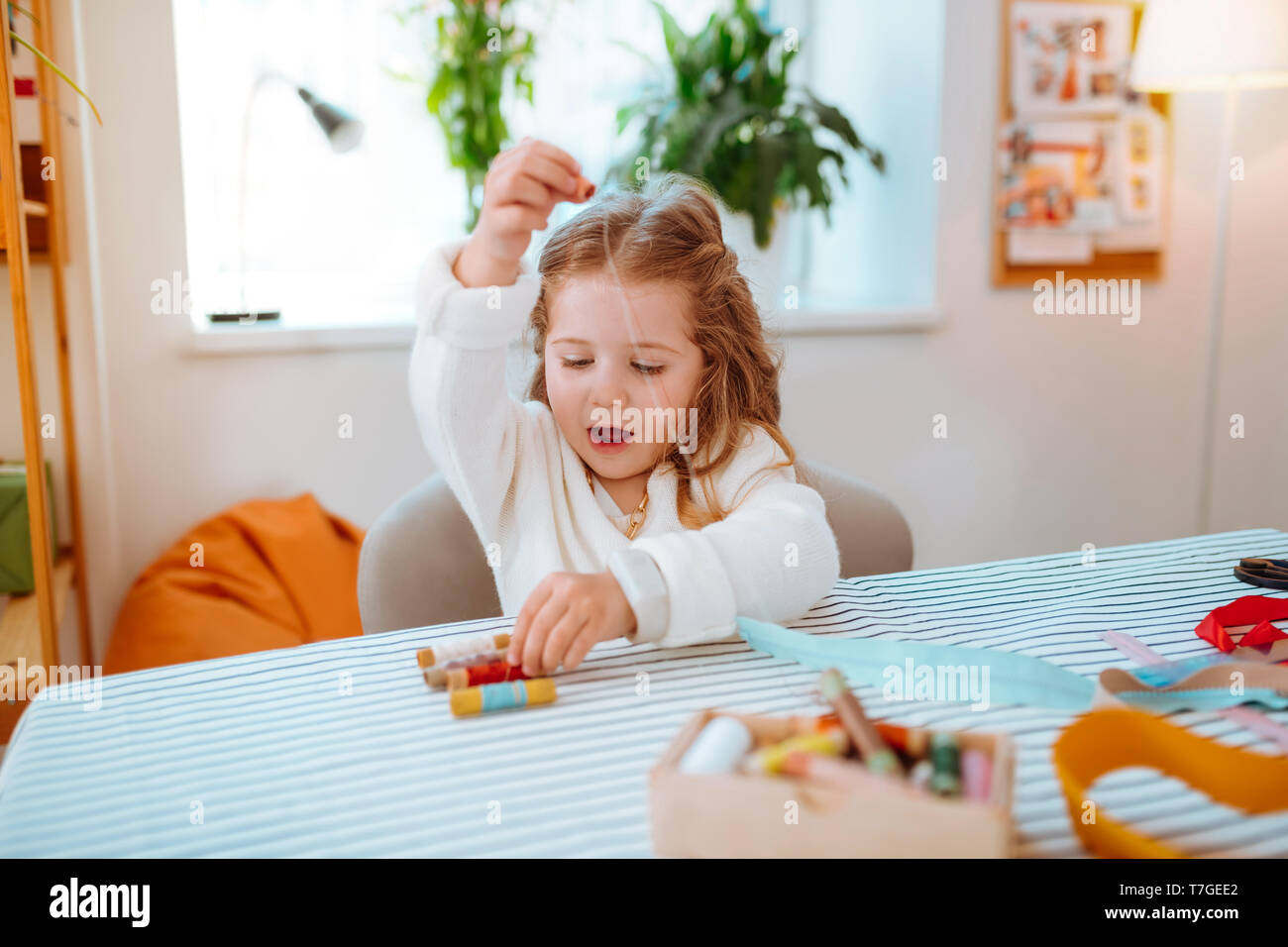 Girl feeling involved in playing with threads in atelier of mom Stock ...