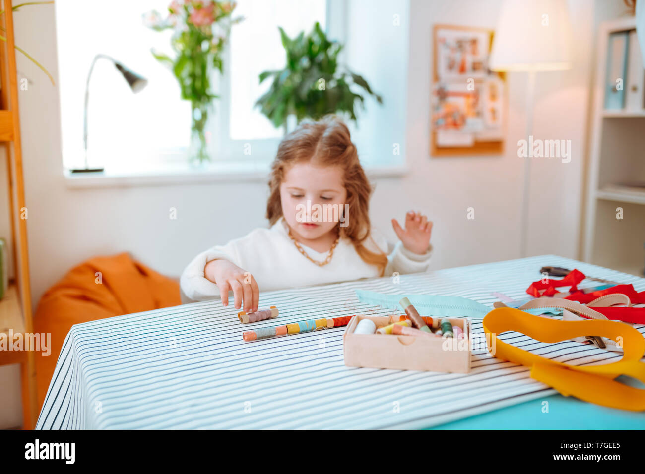 Funny girl playing with colorful threads visiting mom at work Stock ...