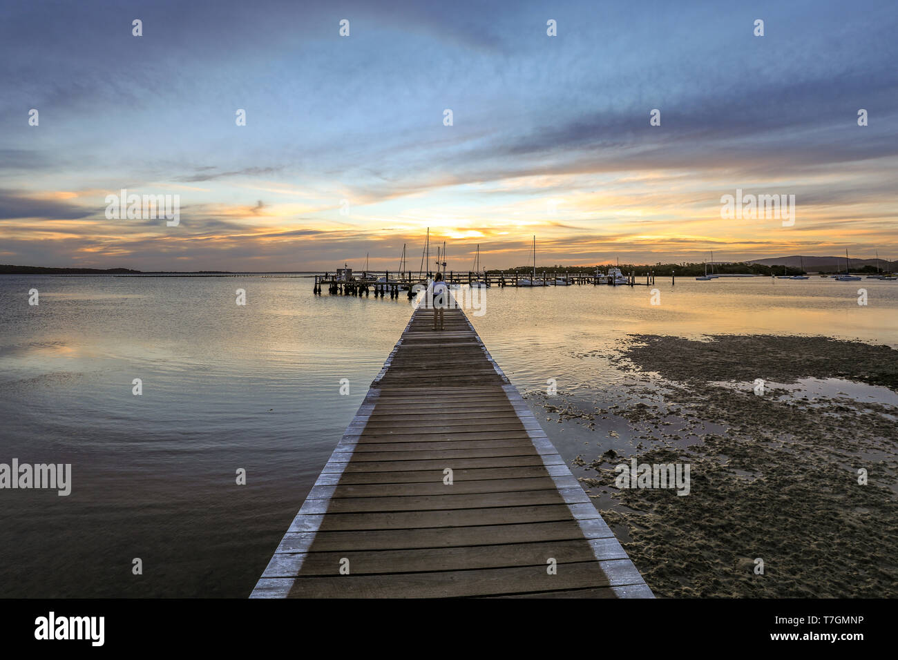 Timber jetty leading to sun setting over ocean Stock Photo - Alamy