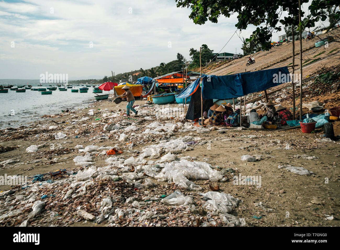 Vietnamese woman throws garbage on the beach by the sea. Dump by the ...