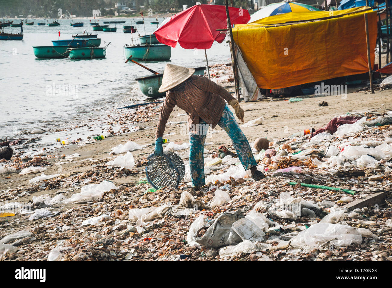 Vietnamese woman throws garbage on the beach by the sea. Dump by the ...