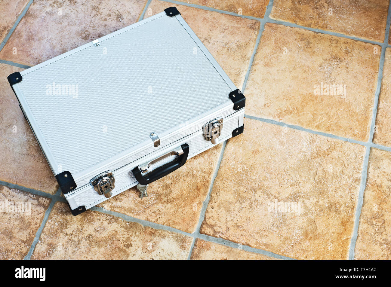 Closed aluminum suitcase on tiled floor Stock Photo - Alamy