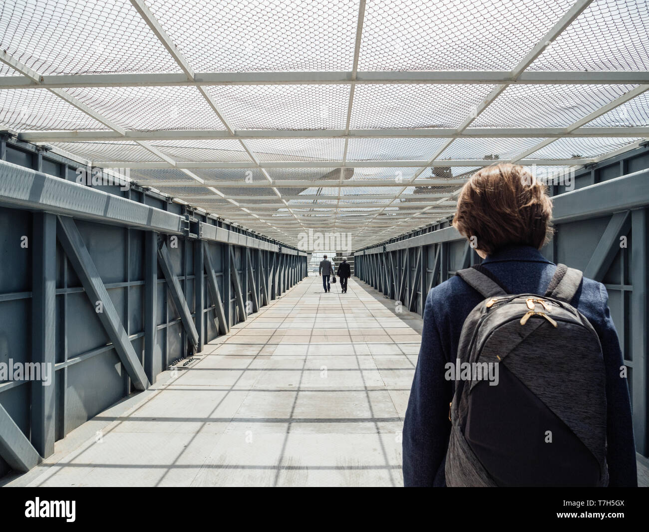Rear view of young tourist caucasian woman crossing bridge street in ...