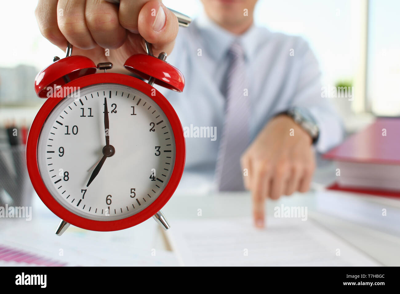 Male hand on the alarm clock a red Stock Photo - Alamy