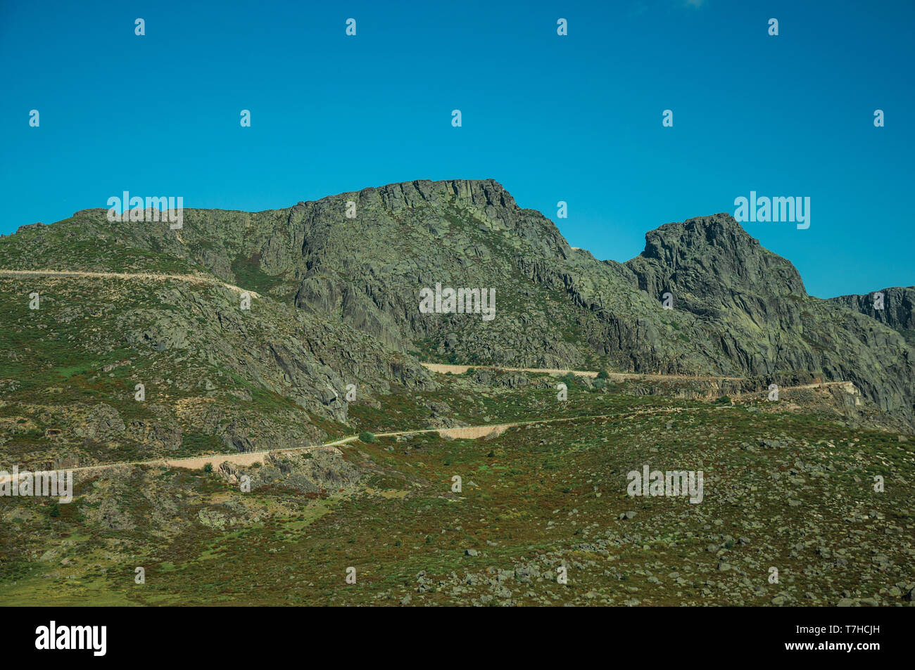 Long roadway passing through rocky landscape and green fields at Serra ...