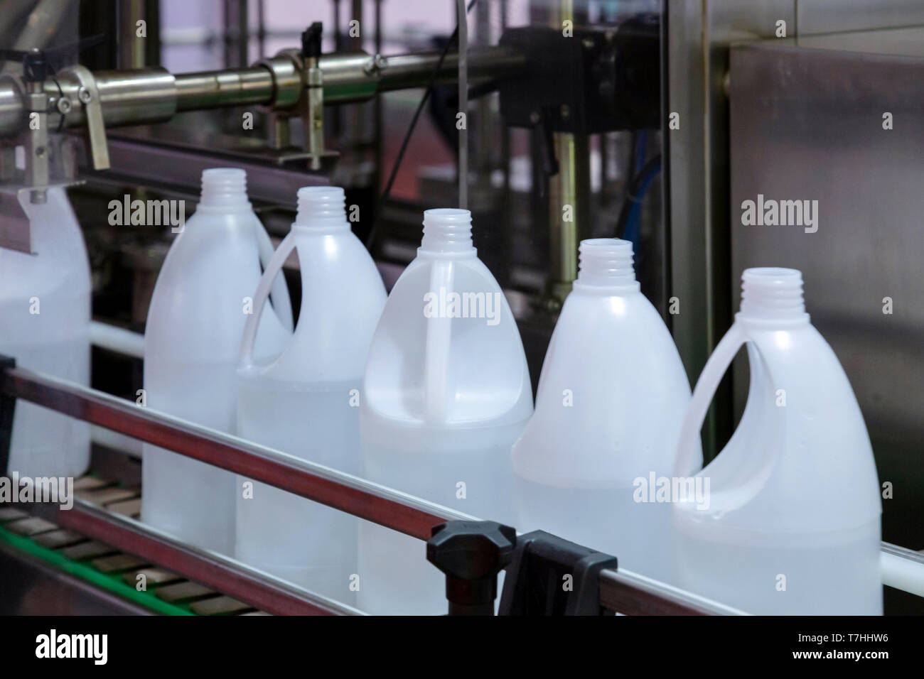 white plastic gallons or bottle on the production line of the conveyor ...
