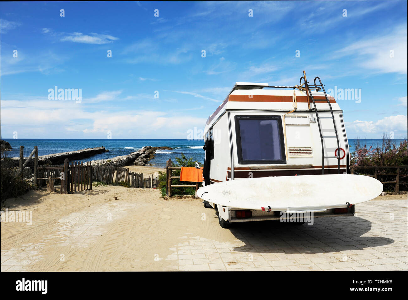 Rear of vintage camper parked on the beach (seaside) with a surfboard ...