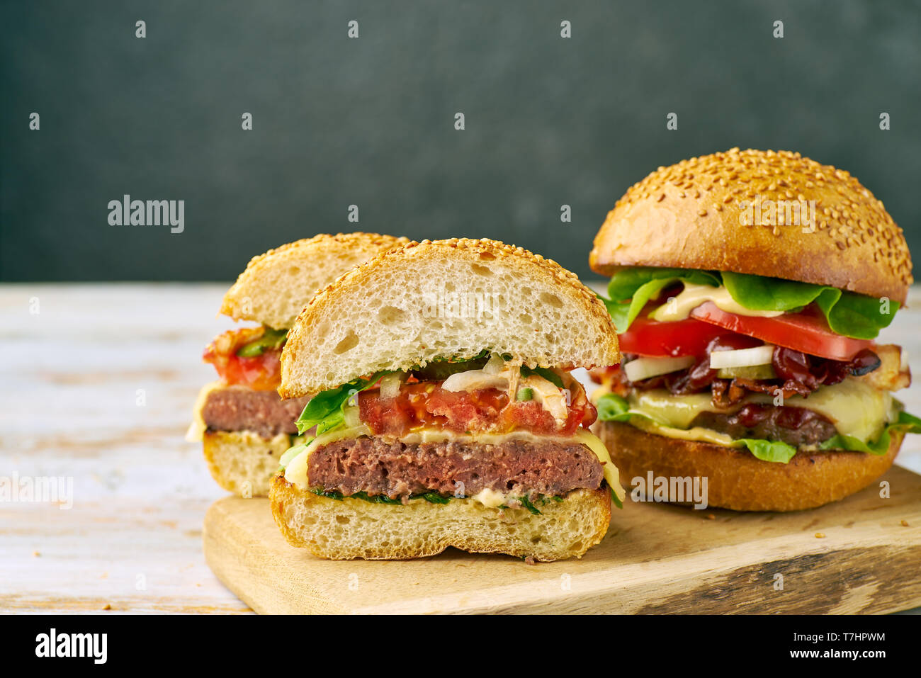 Whole and divided hamburger on old wooden table Stock Photo - Alamy
