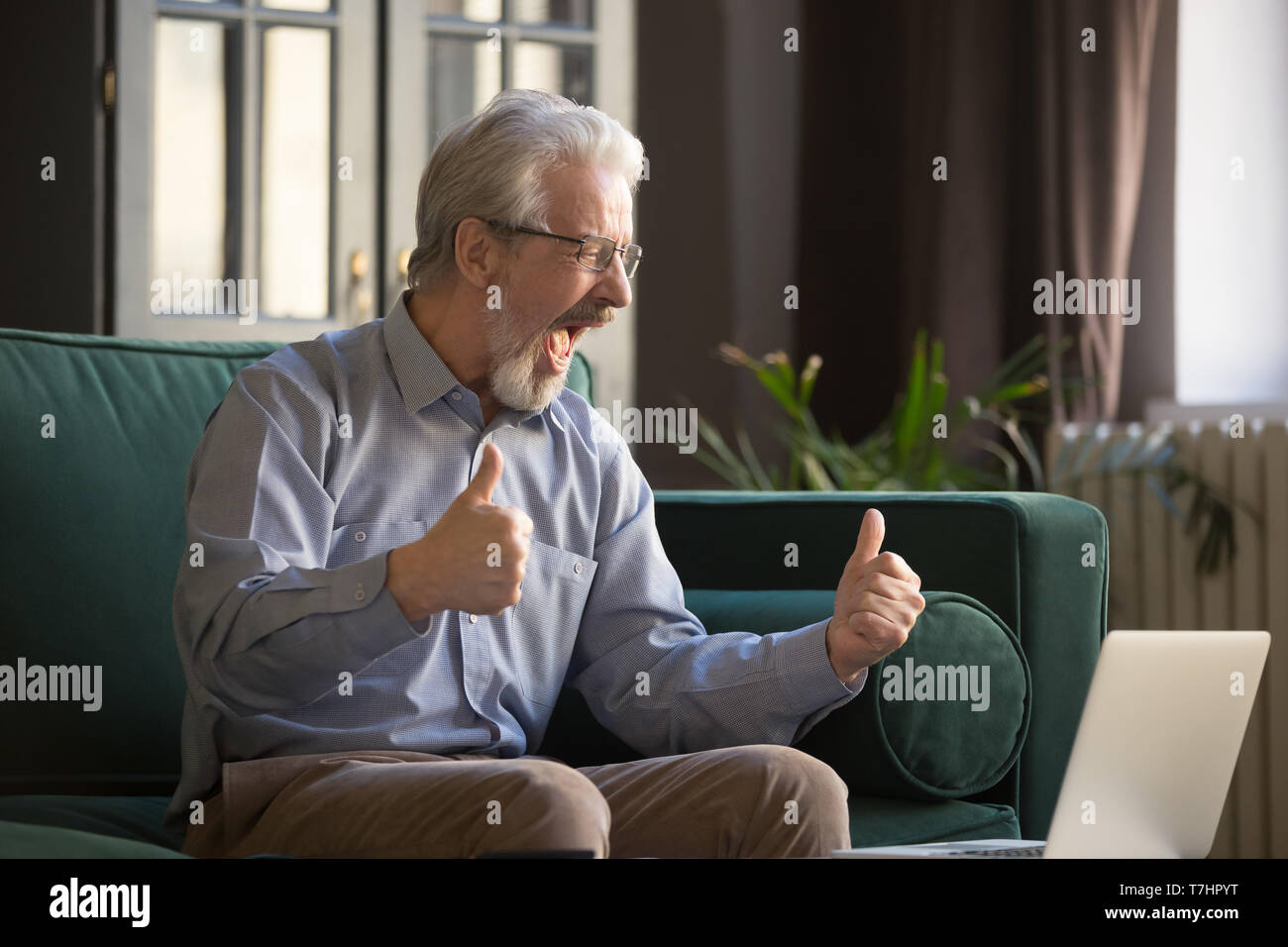 Happy excited grey haired mature man celebrating success, using laptop ...