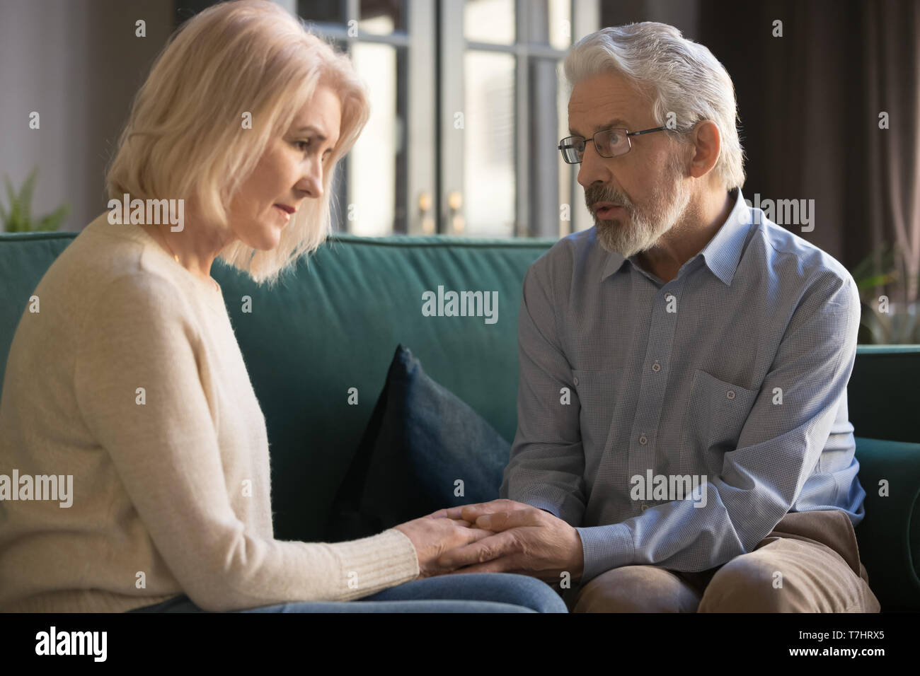 Grey haired husband comforting wife, holding hands, showing support ...