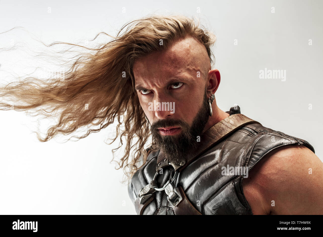 Threatening. Blonde long hair and muscular male model in leather viking ...