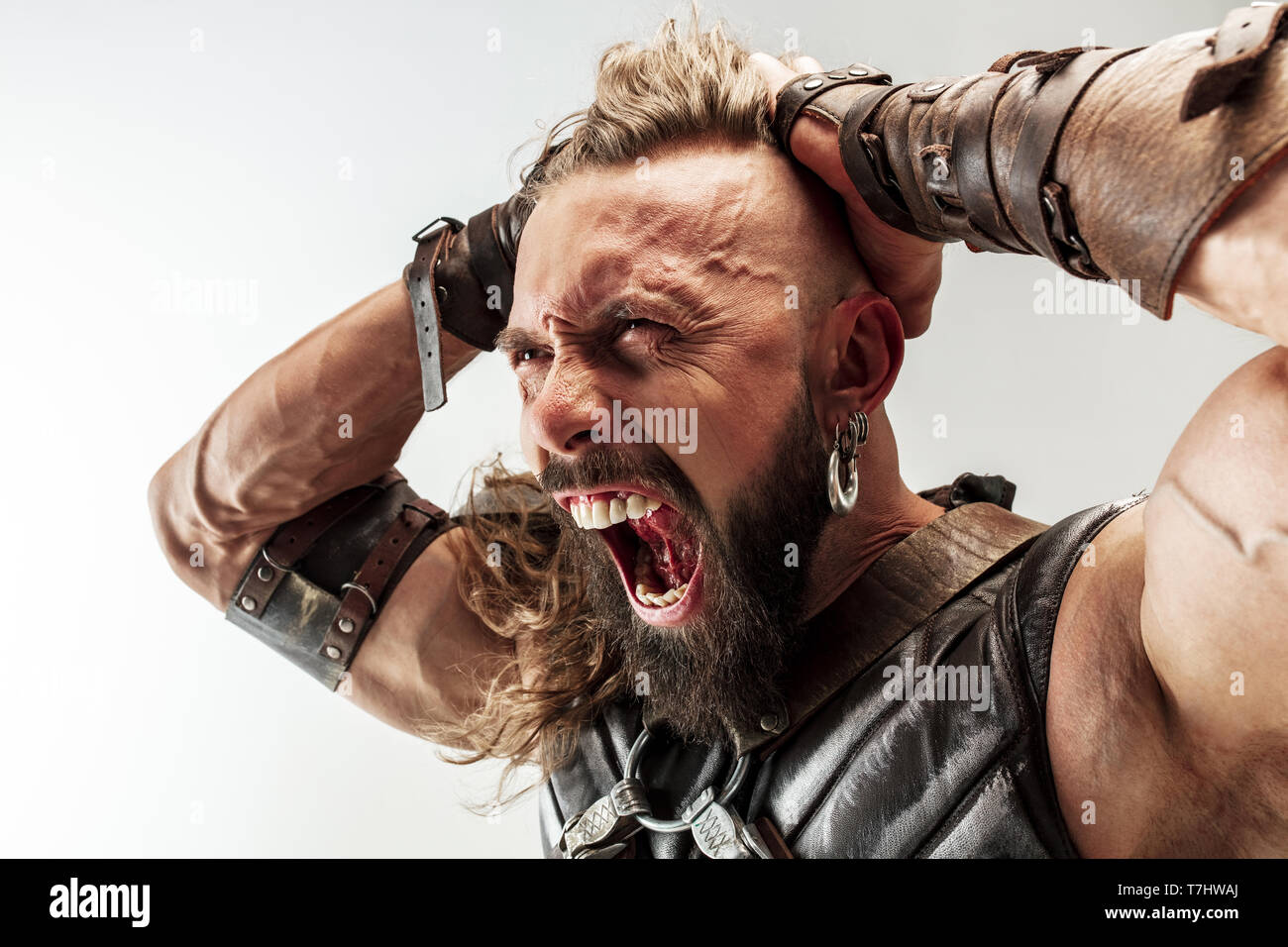 Leader. Blonde long hair and muscular male model in leather viking's ...