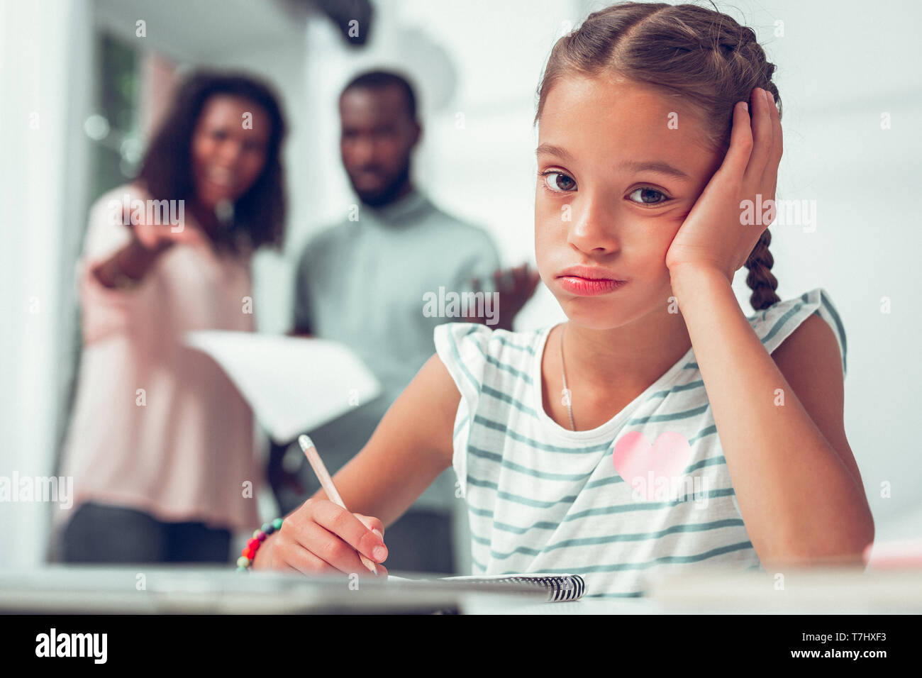 Face portrait of girl doing lessons when her parents talking Stock ...