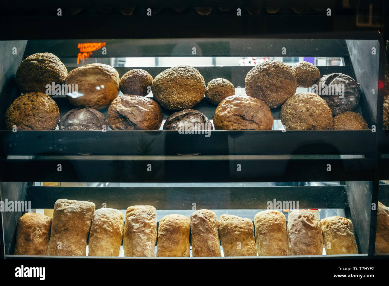 Glass bakery showcase with shelves on which lies bread and buns of ...