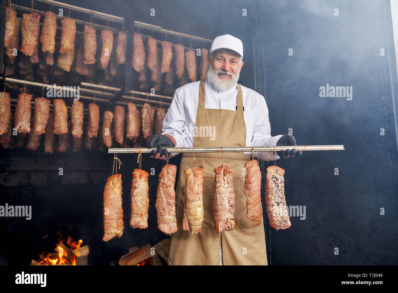 Smoked pieces of meat hanging in row in smokehouse. Smoked meat ...