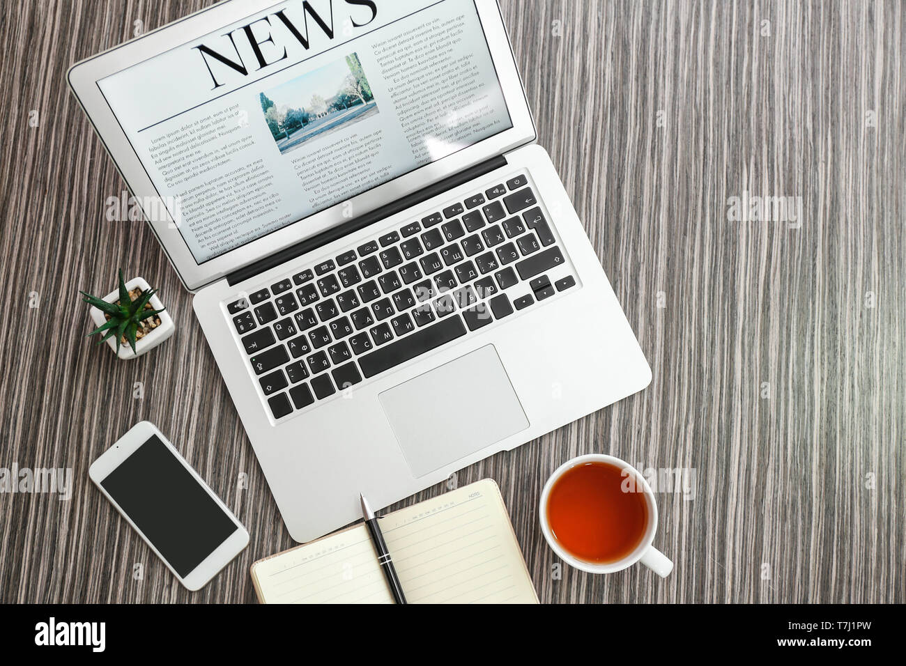 Workplace with laptop and news on screen against wooden background ...