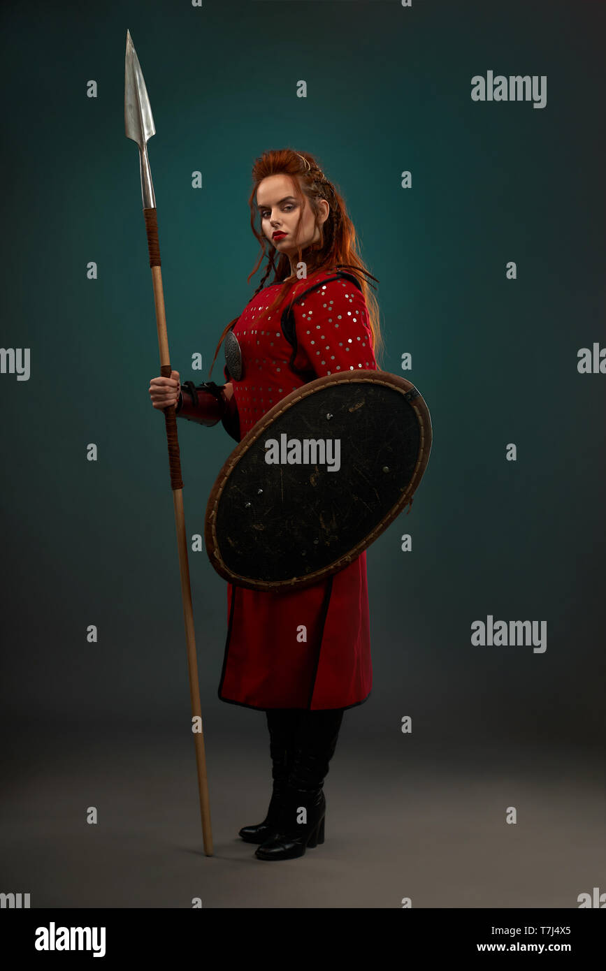 Brave female warrior with serious facial expression holding long spear ...