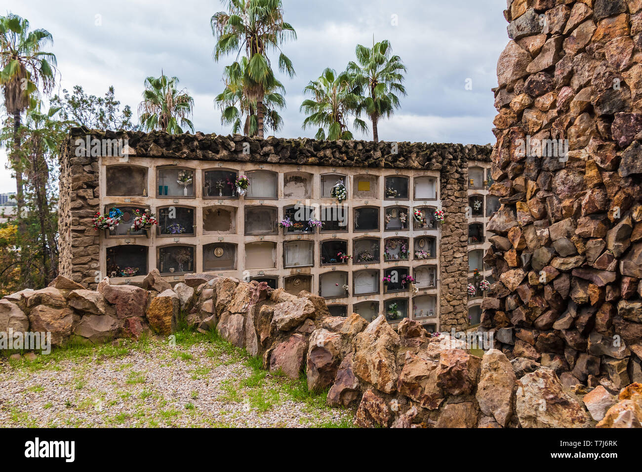 The stone walls with graves on the Montjuic Cemetery in overcast day ...