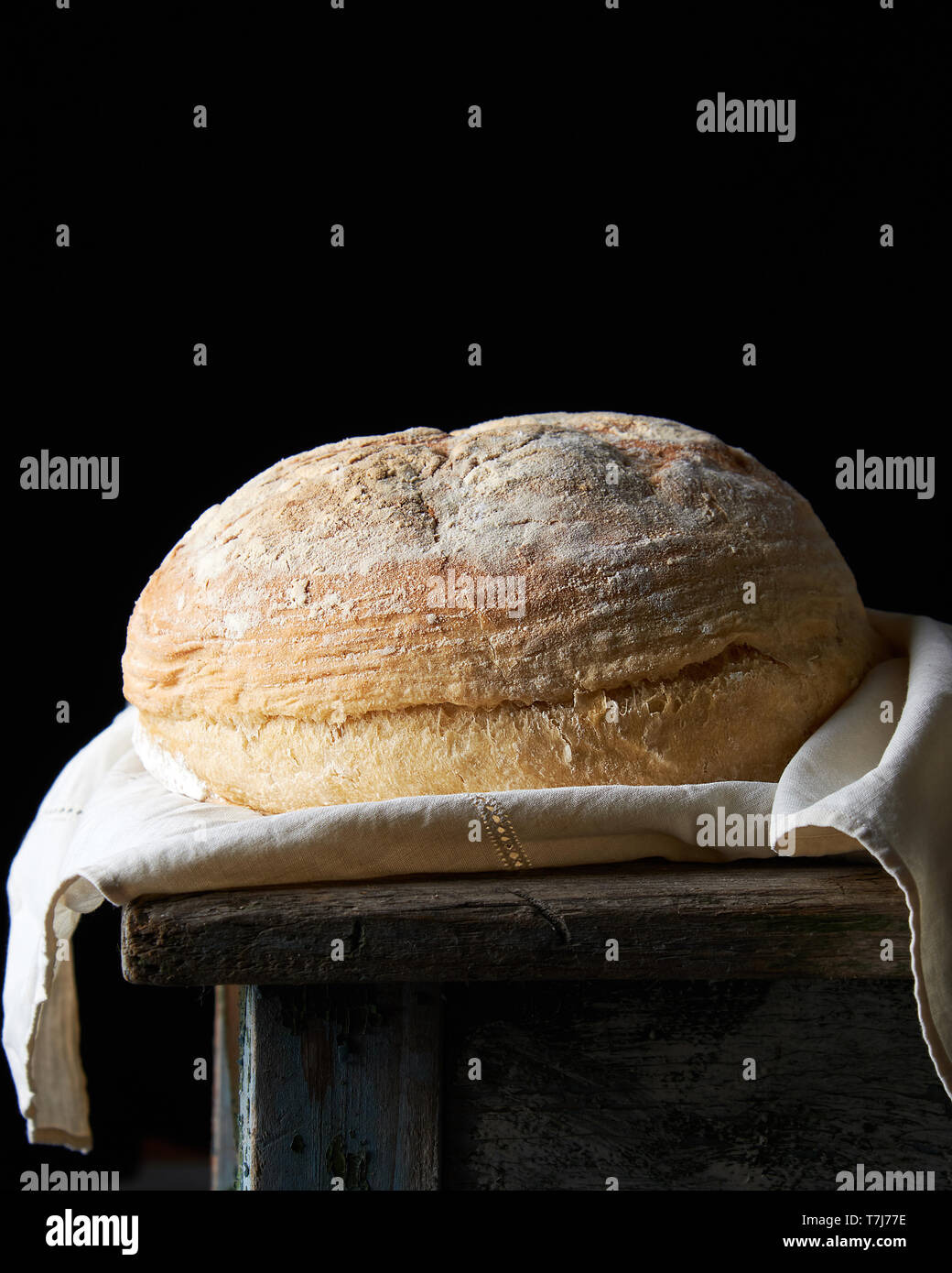 baked round white wheat bread on a textile towel, wooden old table ...