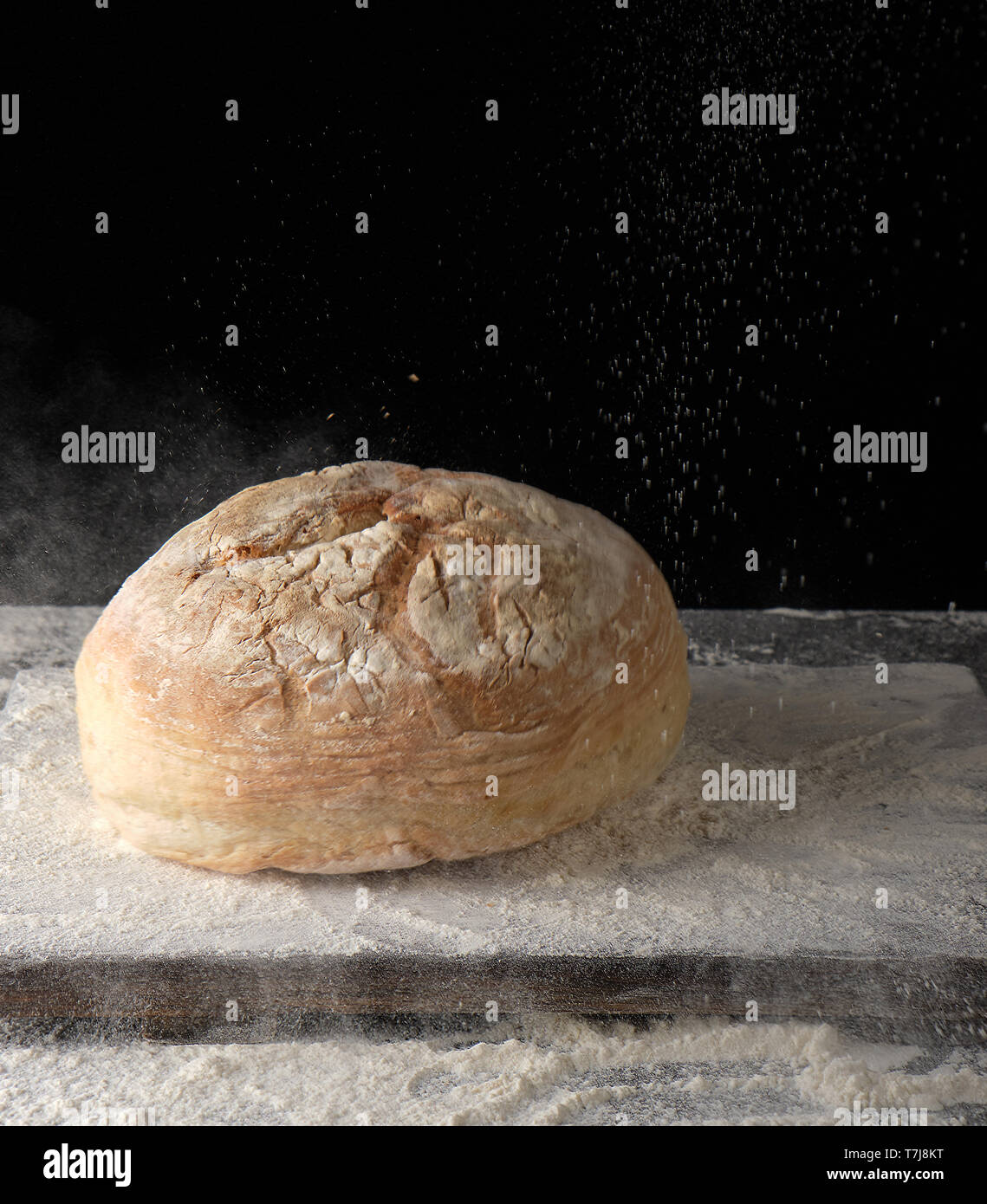 baked round bread in sprinkles of white flour, black background Stock ...