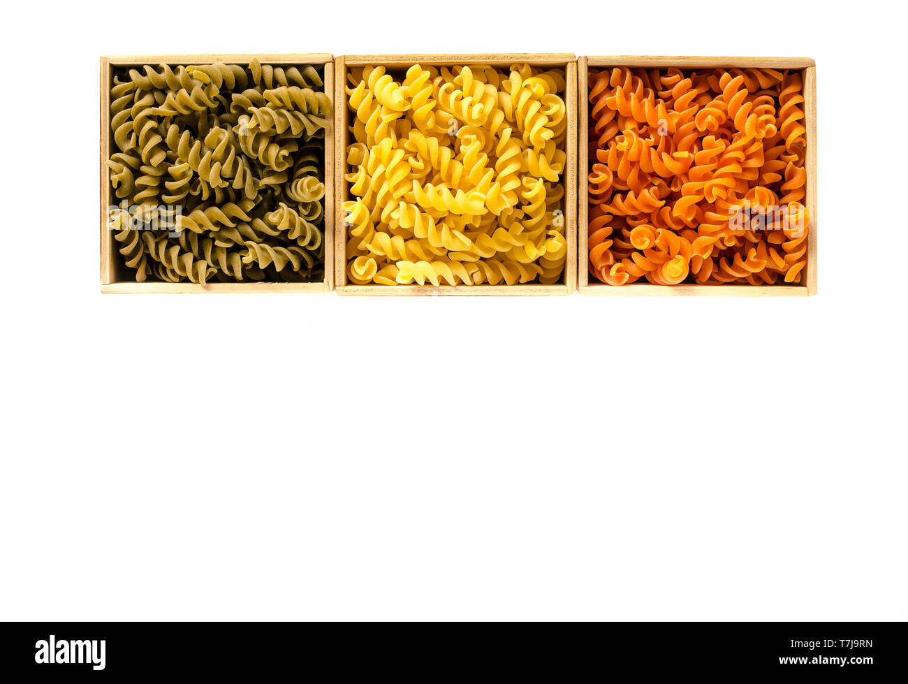 Multi-colored pasta in the form of spirals lie in wooden boxes that ...